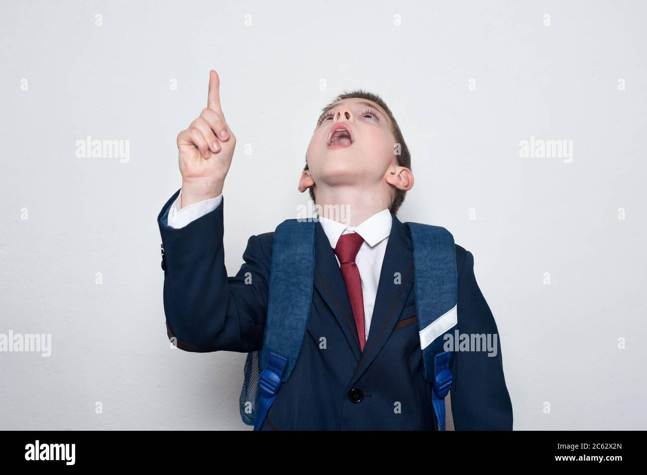 Student in school uniform shows an index finger up.. Boy stares upwards ...
