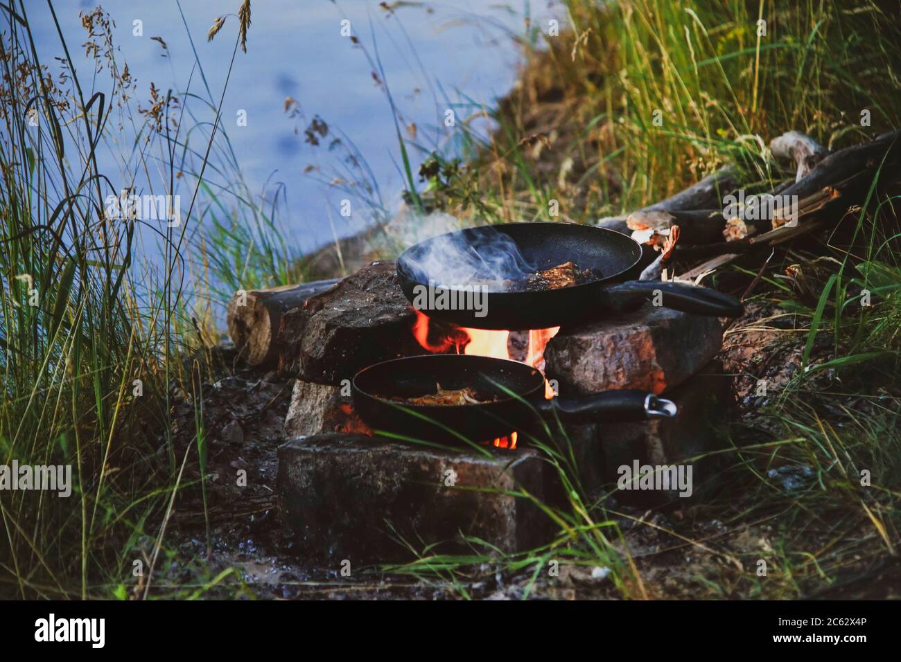 Fish in a pan is fried on a fire on the river bank. Dinner by the river ...