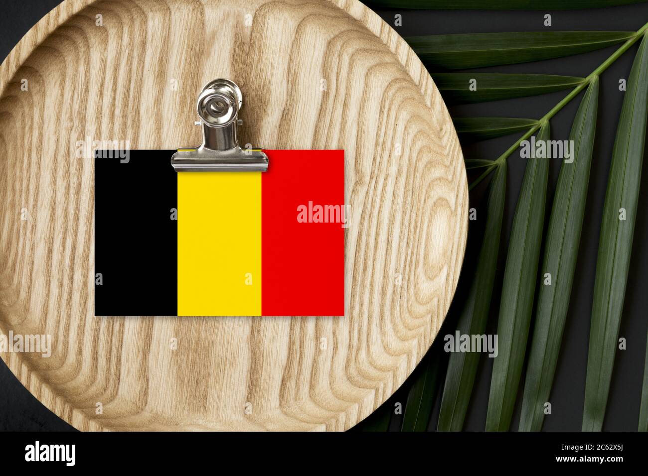 Belgium flag tagged on wooden plate. Tropical palm leaves monstera on ...