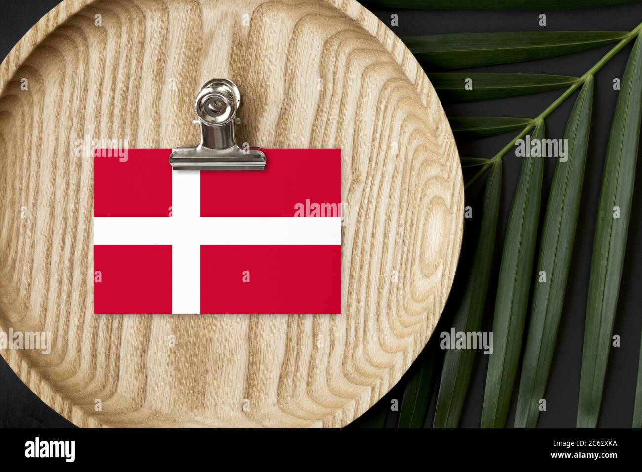 Denmark flag tagged on wooden plate. Tropical palm leaves monstera on ...