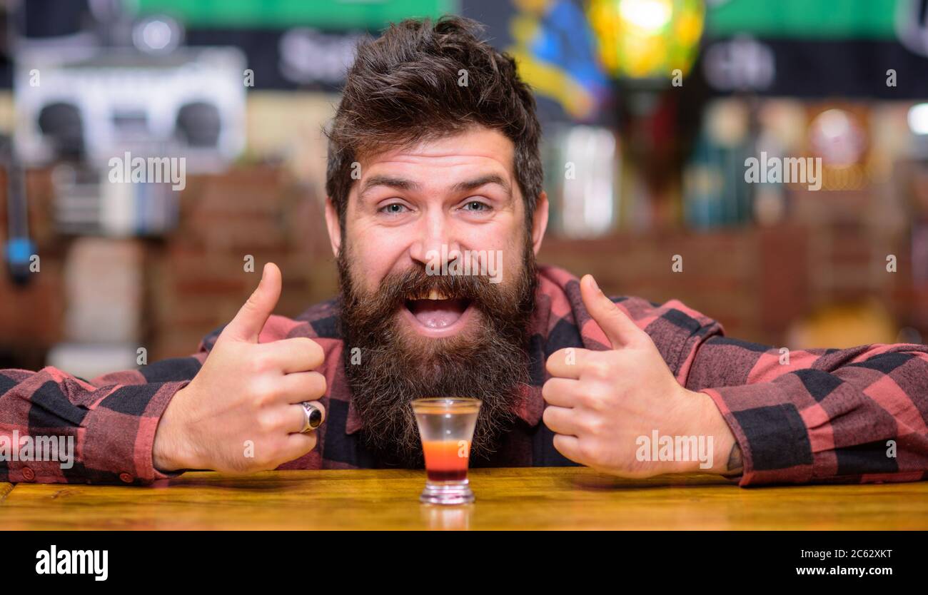 Alcohol and fun concept. Cheerful man near bar counter shows thumbs up ...