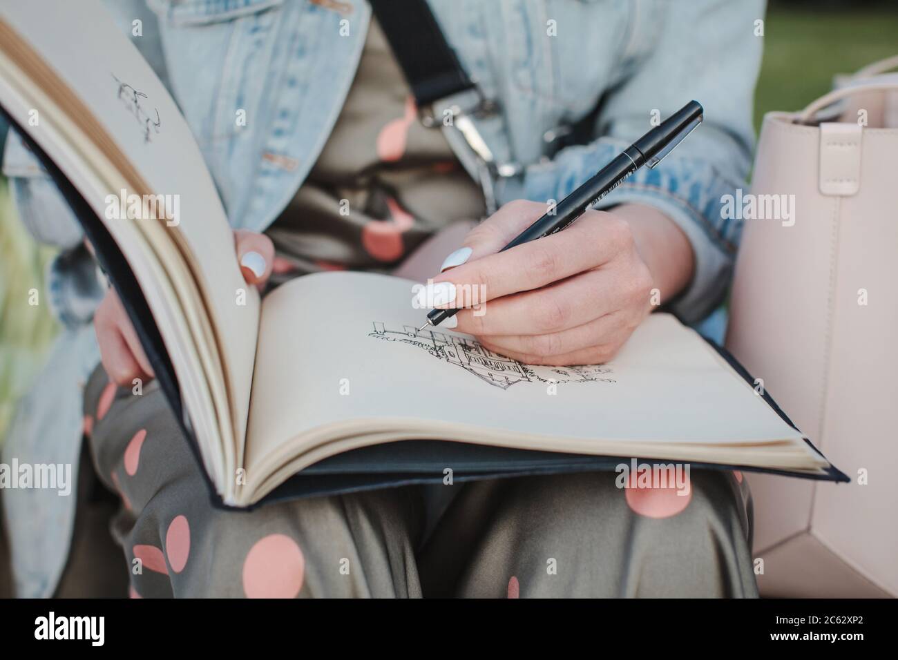 Sketchbook with a drawing of a house close-up. Girl draws in the fresh ...
