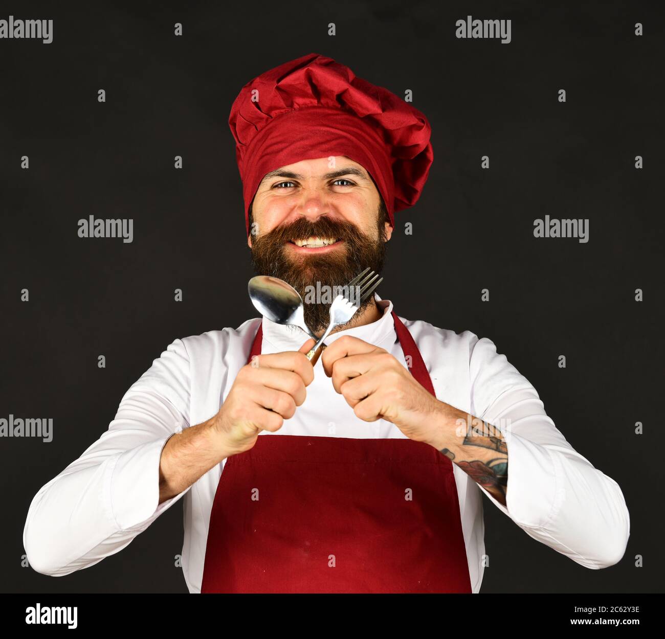 Man with beard holds kitchenware on black background. Cook with smiling ...