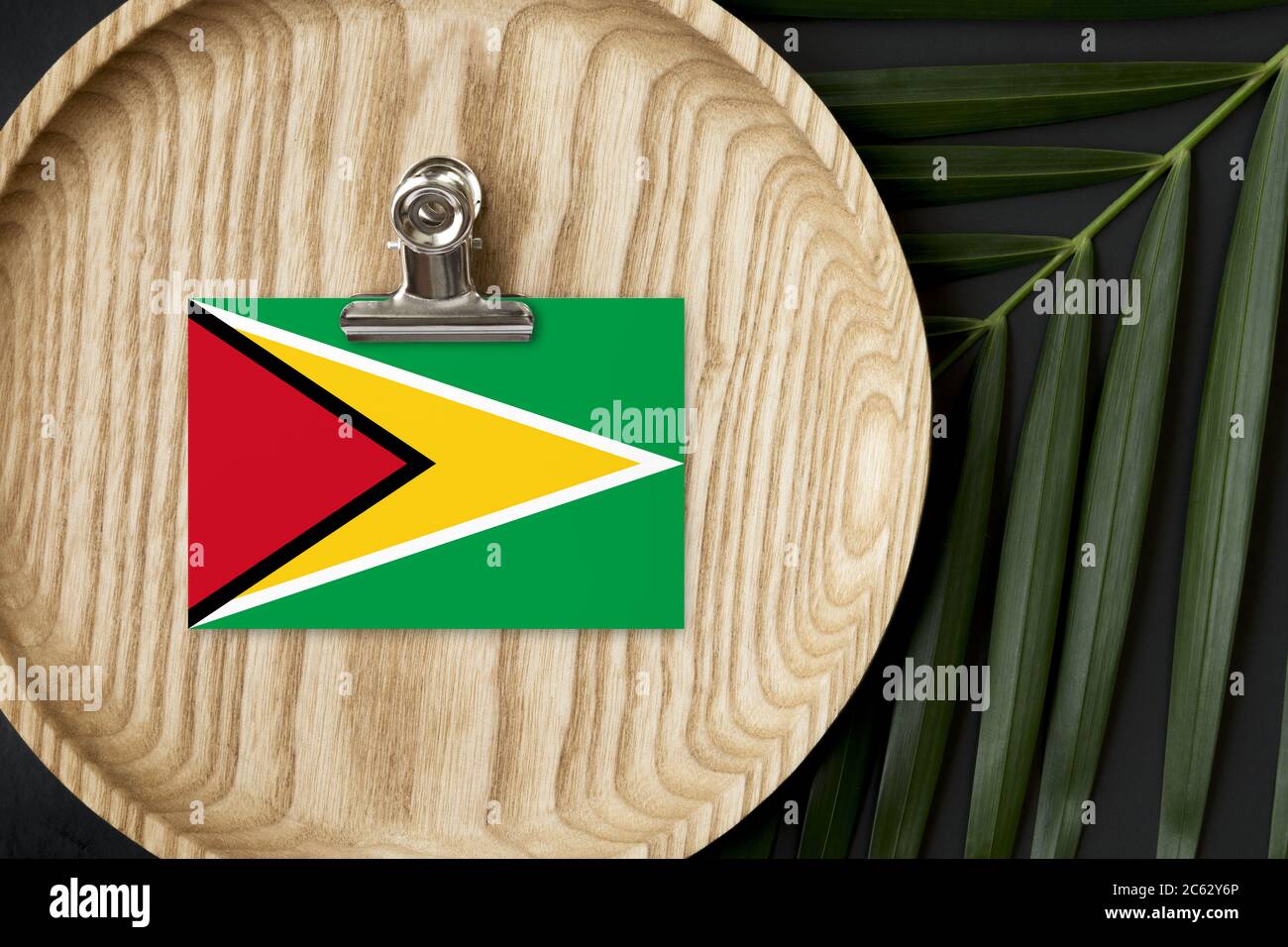 Guyana flag tagged on wooden plate. Tropical palm leaves monstera on ...