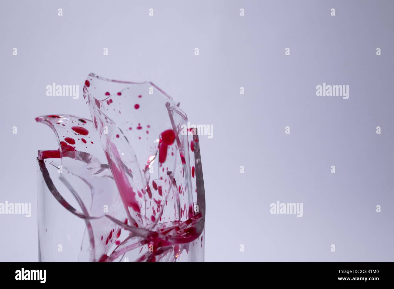 drops of red liquid - blood - on the fragments of a broken glass in a ...