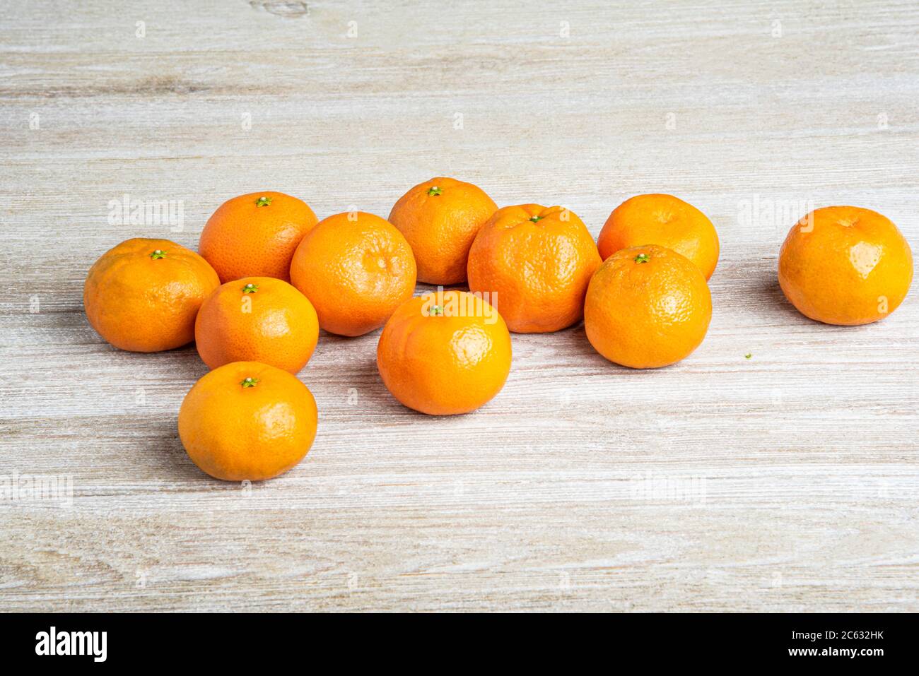 A group of fresh oranges artfully arranged on a white-painted textured ...