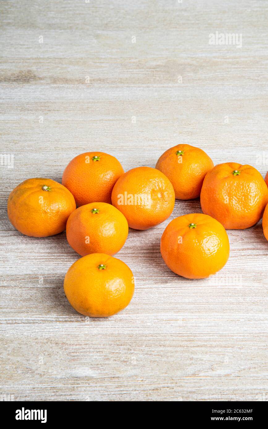 A group of fresh oranges artfully arranged on a white-painted textured ...
