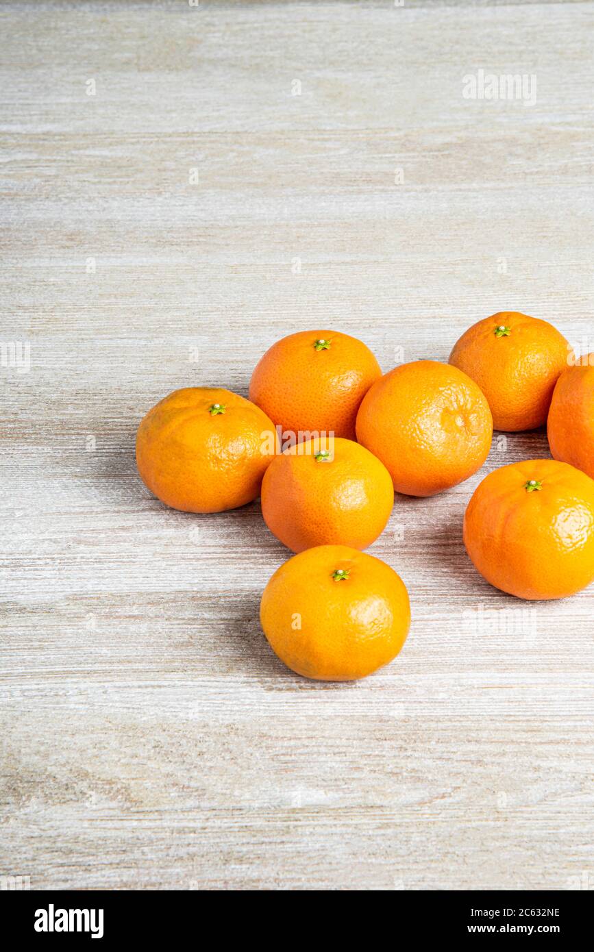 A group of fresh oranges artfully arranged on a white-painted textured ...