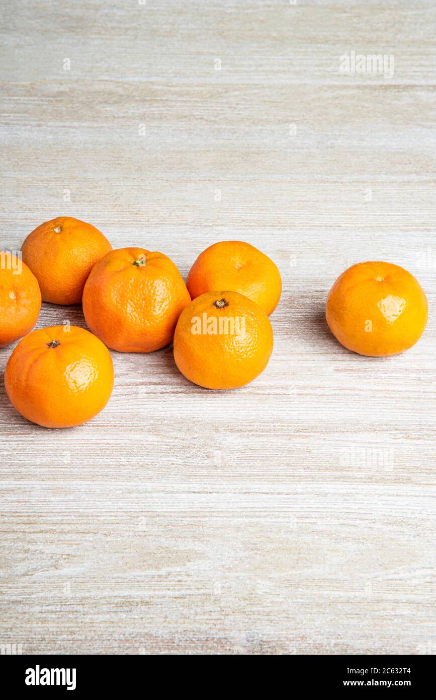A group of fresh oranges artfully arranged on a white-painted textured ...