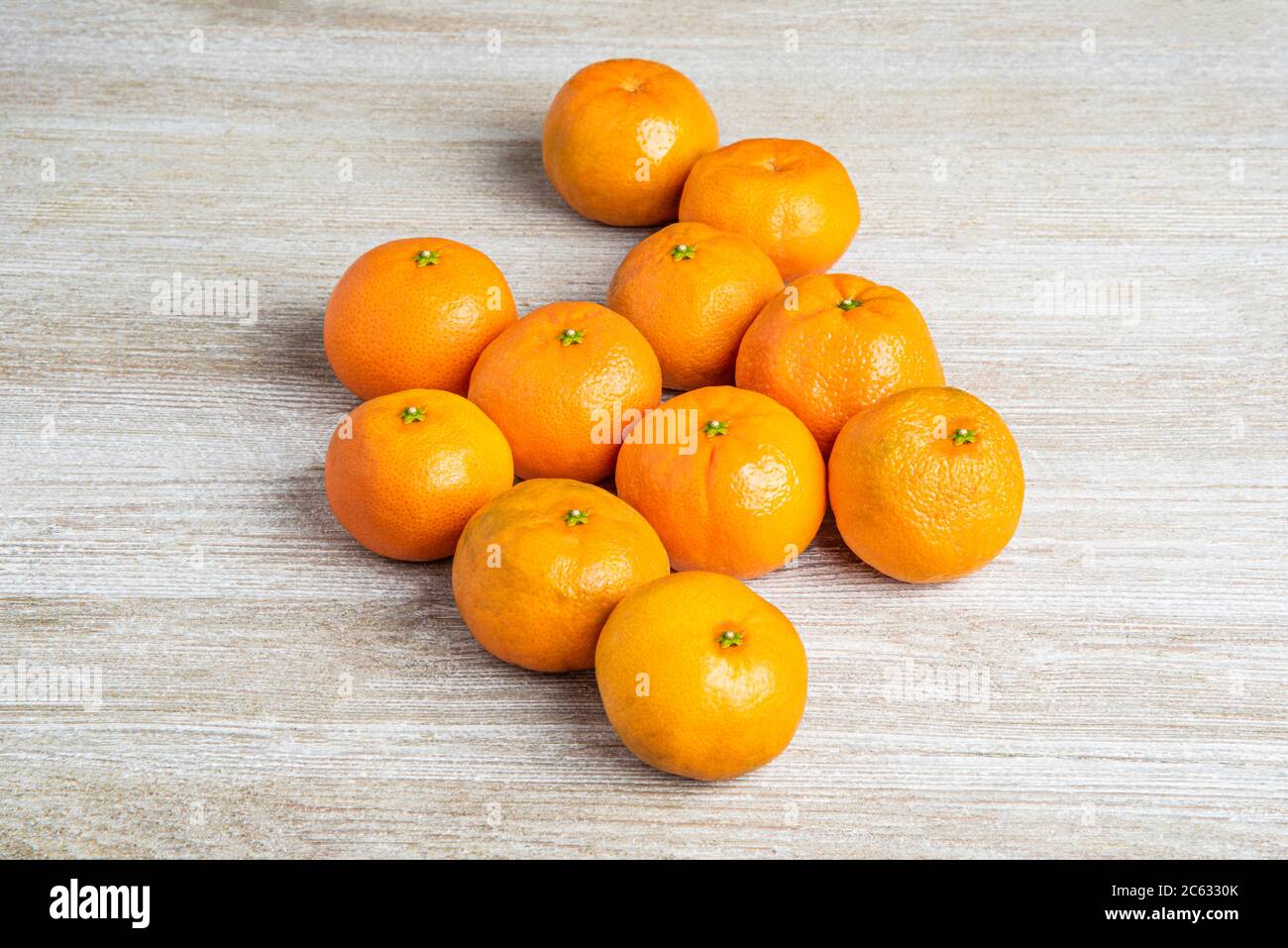 A group of fresh oranges artfully arranged on a white-painted textured ...