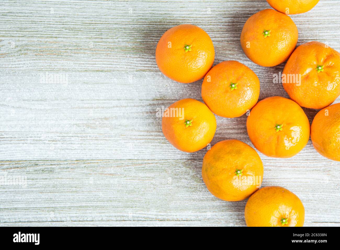 A group of fresh oranges artfully arranged on a white-painted textured ...