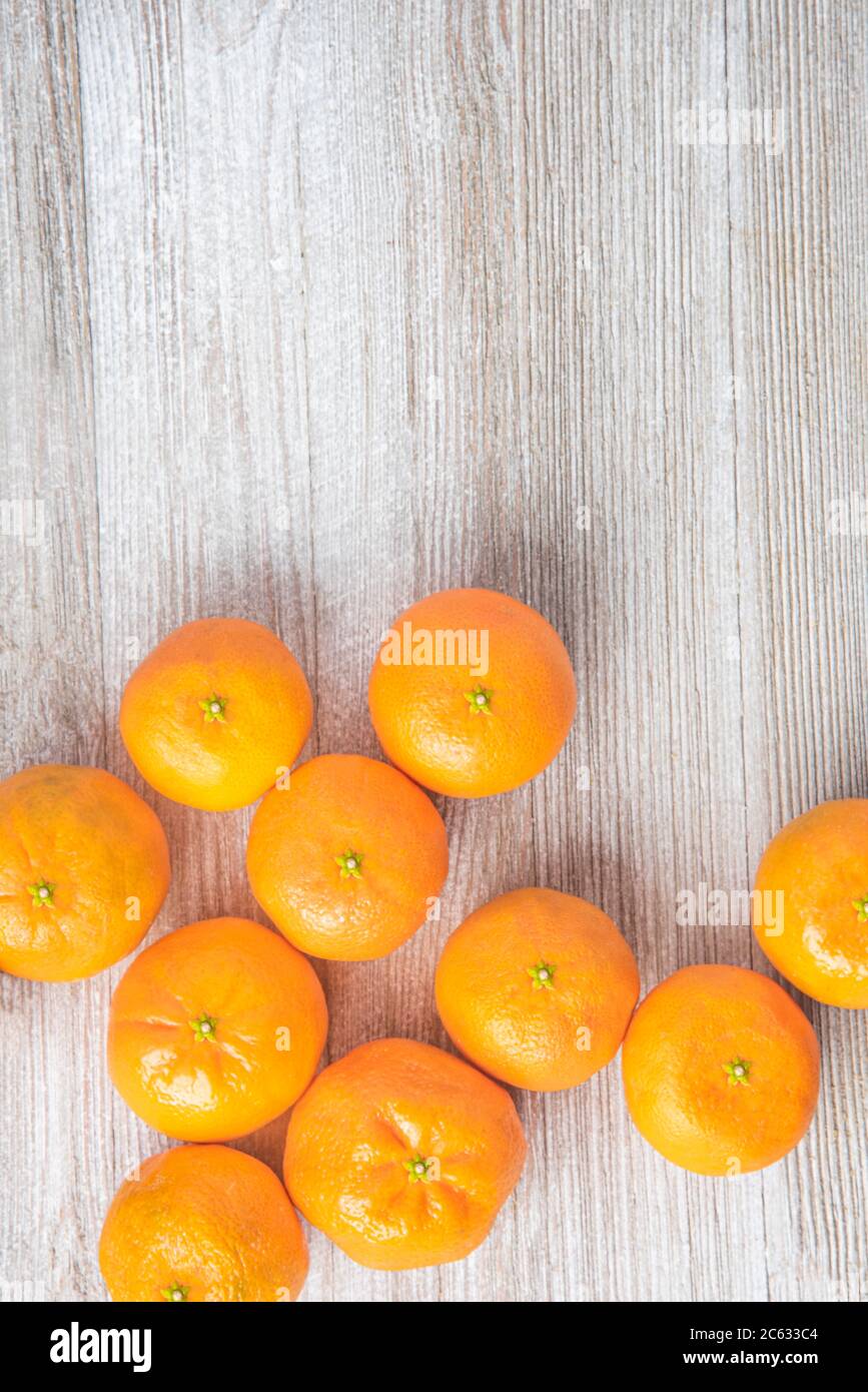 A group of fresh oranges artfully arranged on a white-painted textured ...