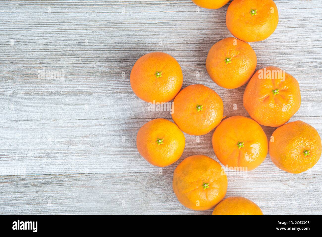 A group of fresh oranges artfully arranged on a white-painted textured ...