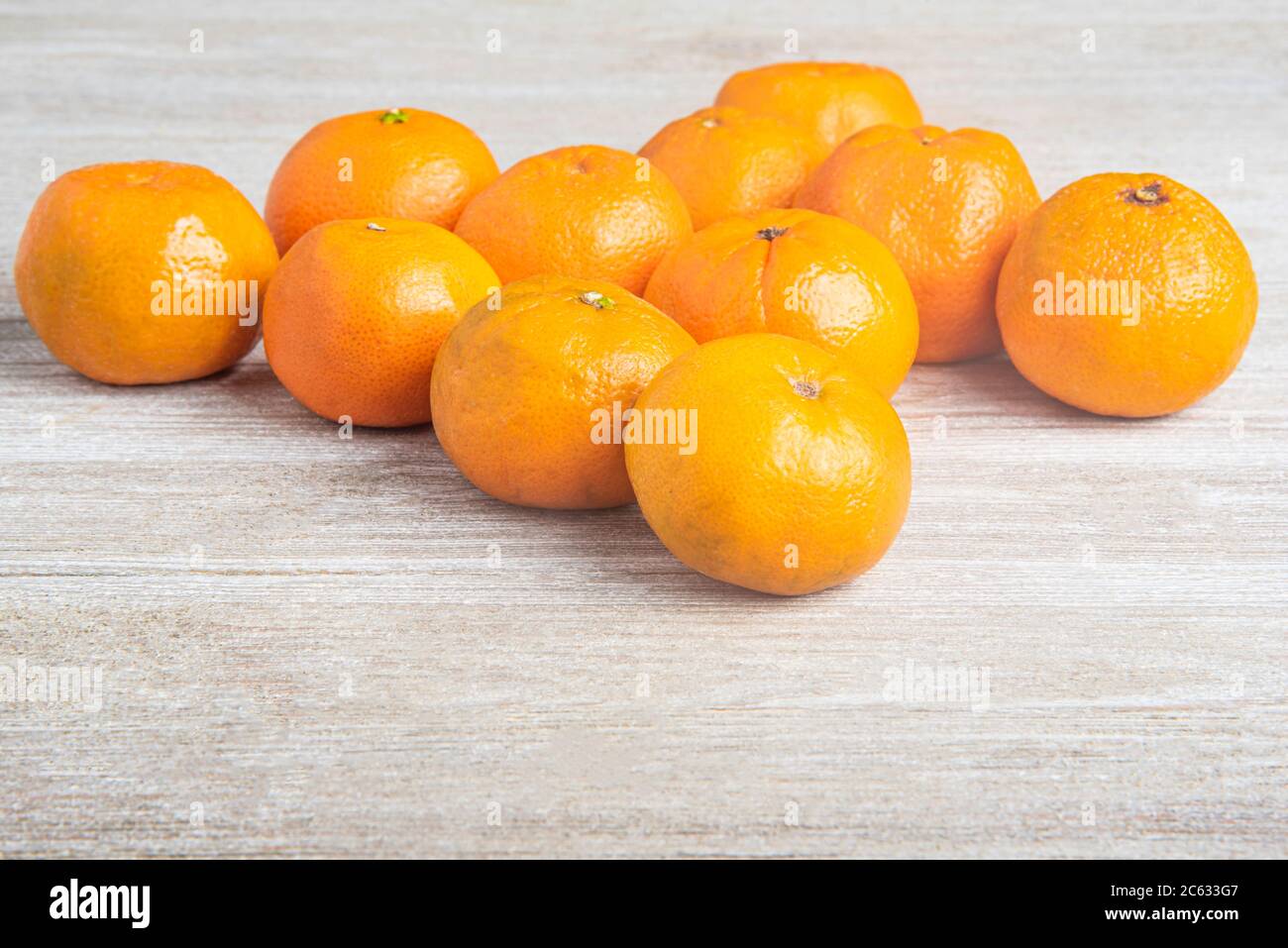 A group of fresh oranges artfully arranged on a white-painted textured ...
