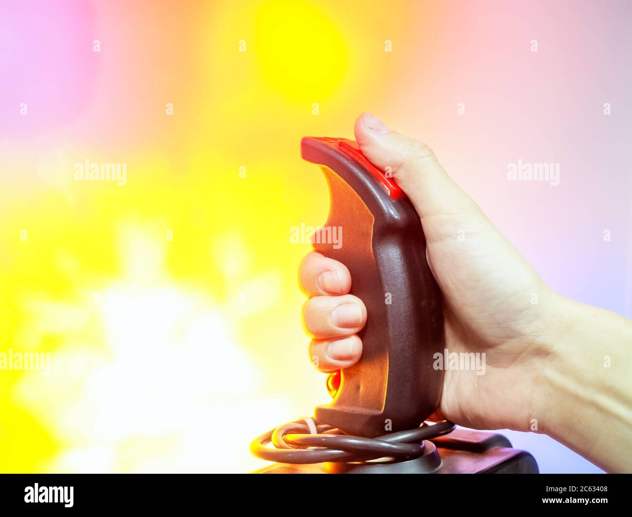 A hand holds a joystick for games by pressing the red button with a ...