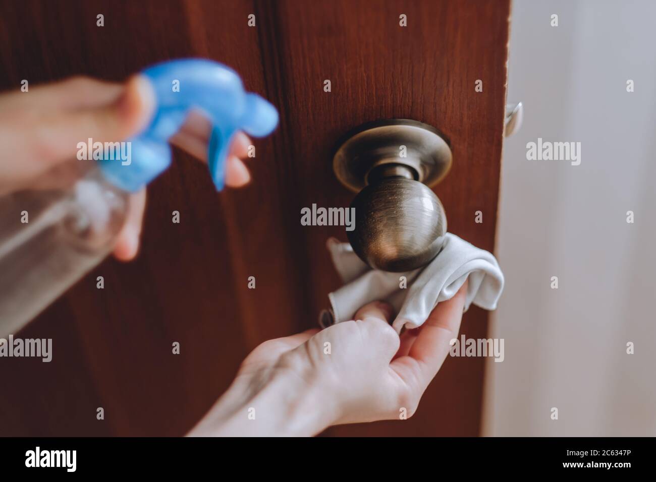 Woman cleans the door handle with an antibacterial spray Stock Photo ...