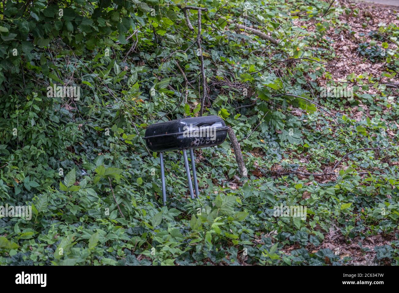 A portable black barbecue grill dumped and left to rot in the woodlands ...