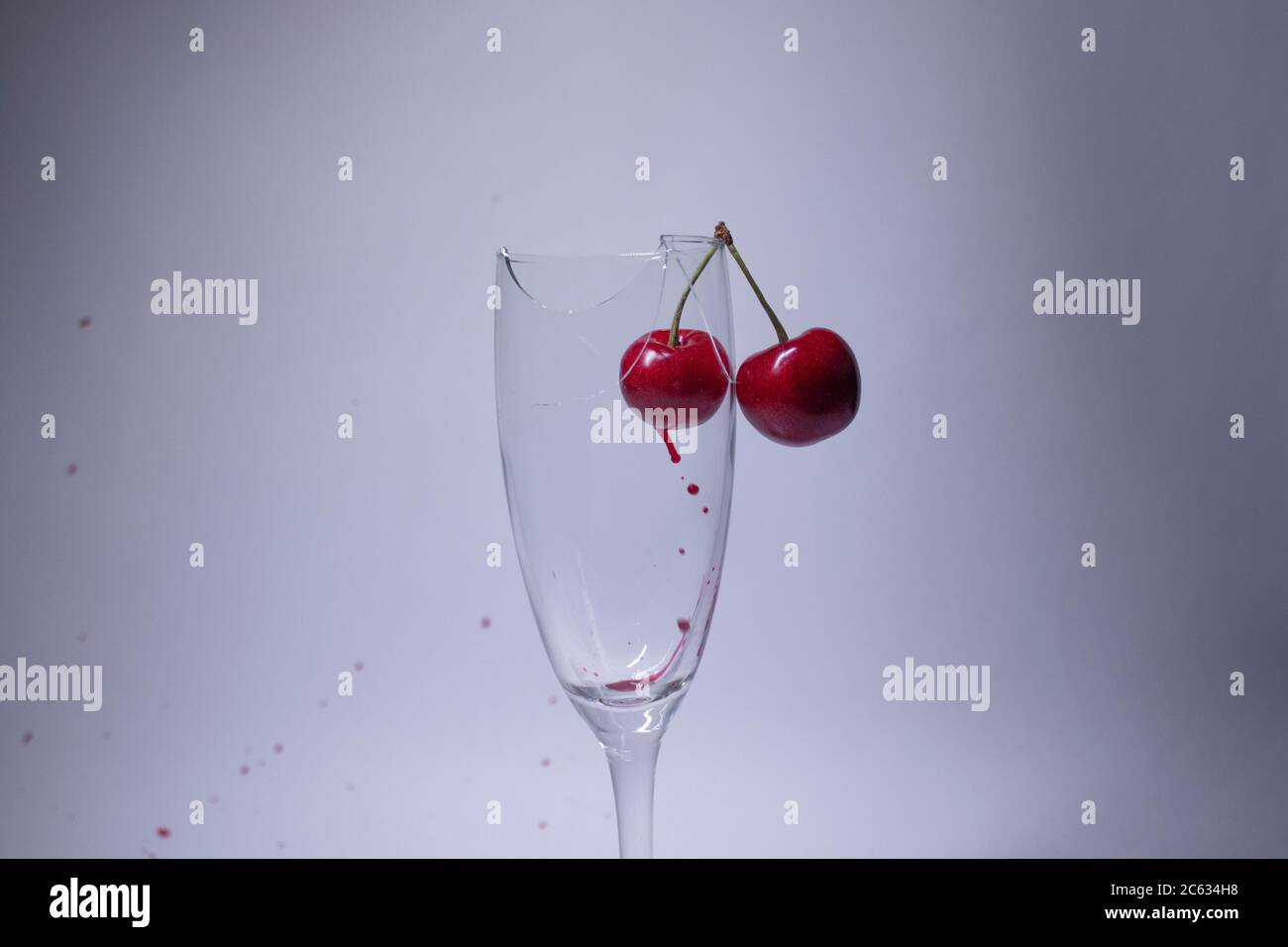 drops of red liquid - blood - in a broken champagne glass with a cherry ...