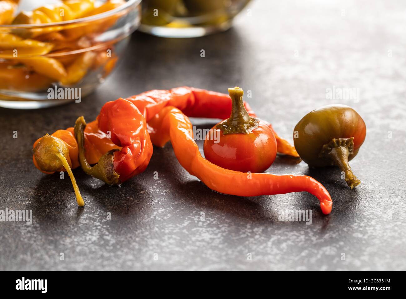 Pickled chili peppers on black kitchen table Stock Photo - Alamy