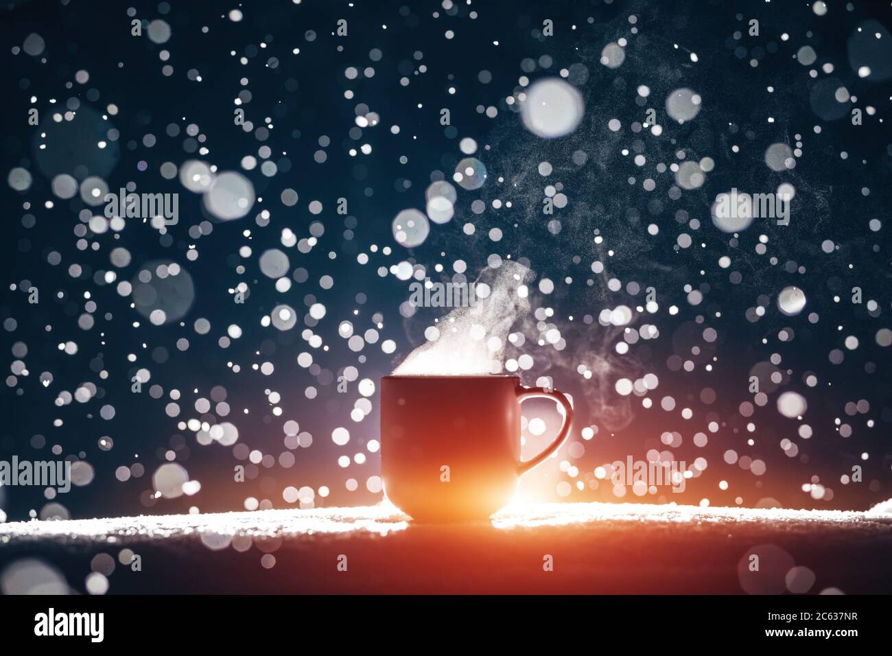 backlighted cup of hot steaming coffee drink or tea on night snowy ...