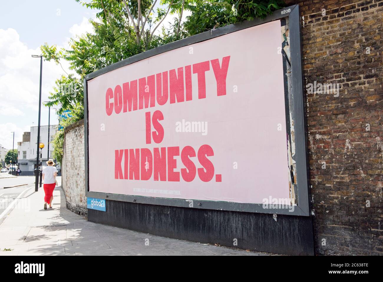 Lady passing Poster saying Community is kindness by Jack Arts put up to ...