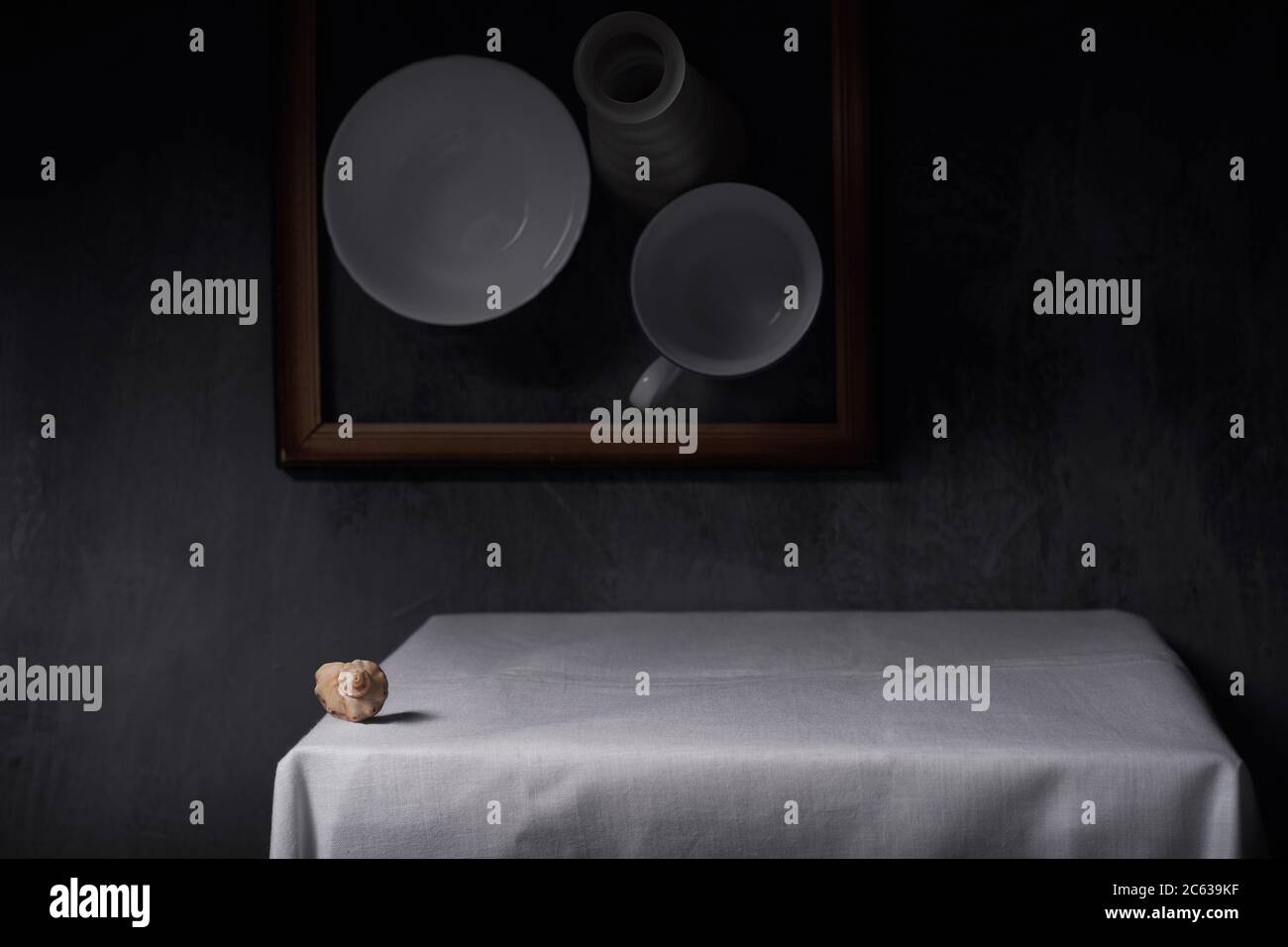 Still life with a shell on a table covered with a white tablecloth ...