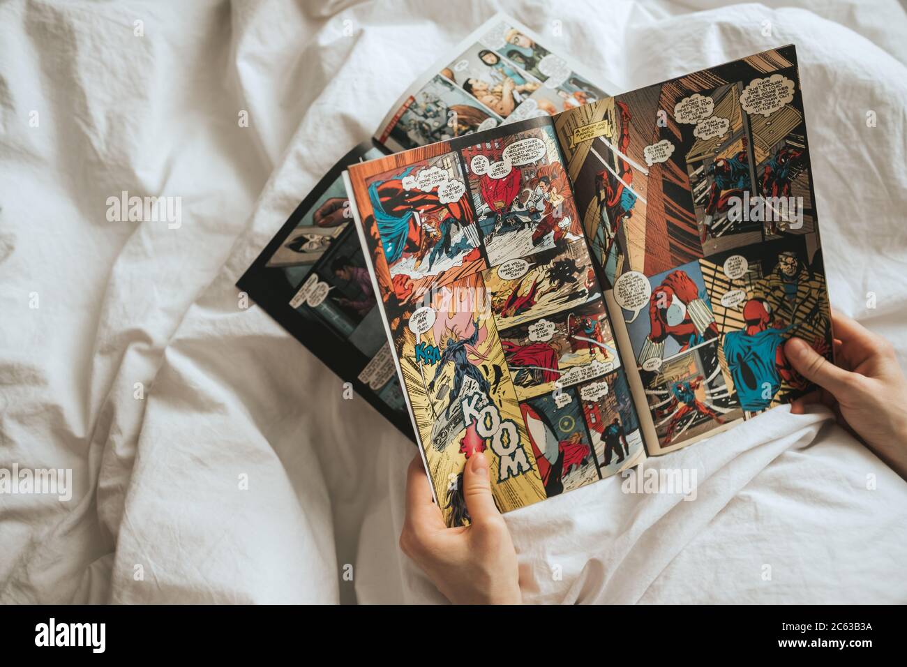 Woman reads comics in bed Stock Photo - Alamy
