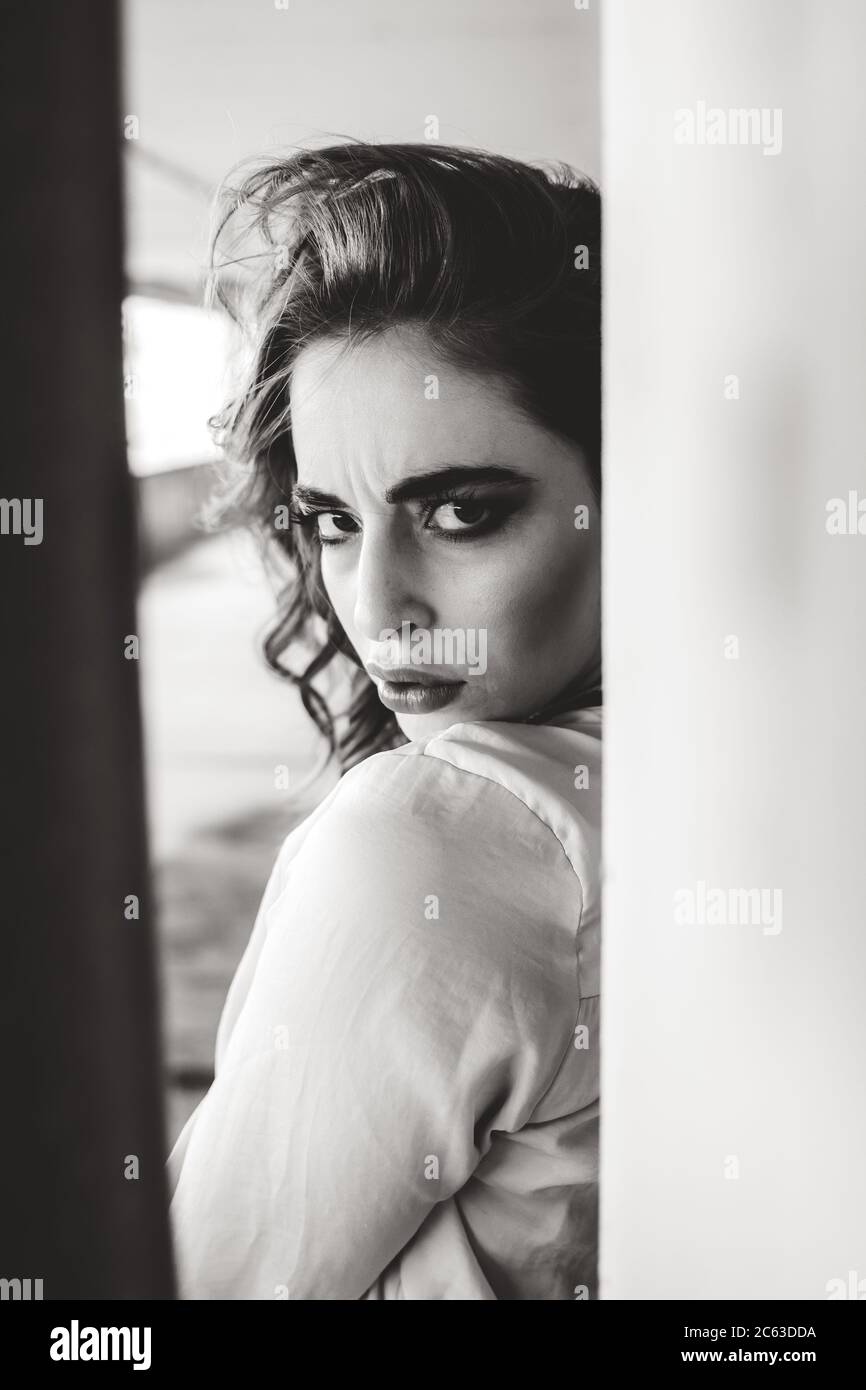 Black and white photo of frowning young woman looking over her shoulder ...