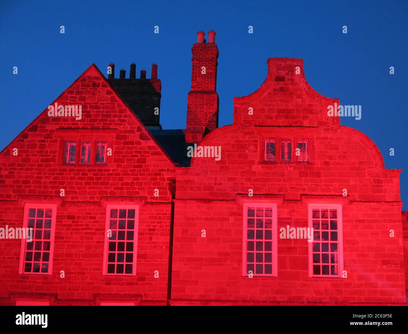 The facade of Delapre Abbey illuminated in red lights at dusk Stock ...