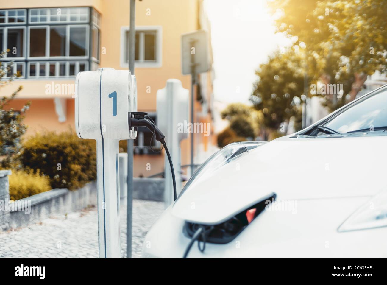 An electric car charging on a parking lot with a charging station in ...