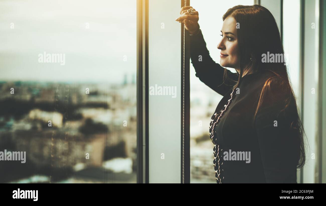 Side view of a charming caucasian woman leaning against the window ...
