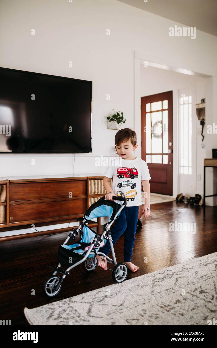 Young boy pushing stroller with stuffed animal in livingroom Stock ...