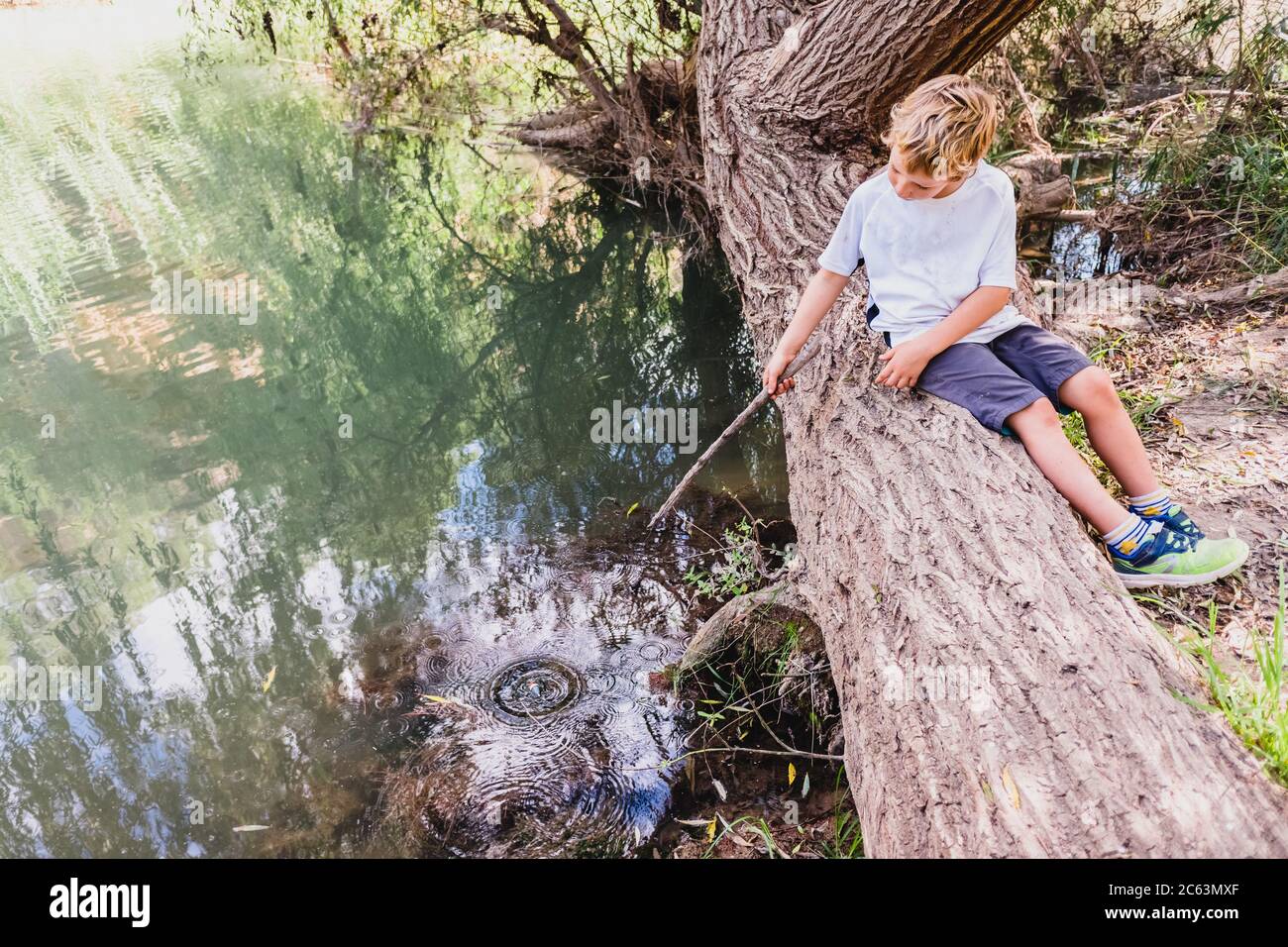 Child waits patiently for a fish to bite from his hook while fishing in ...