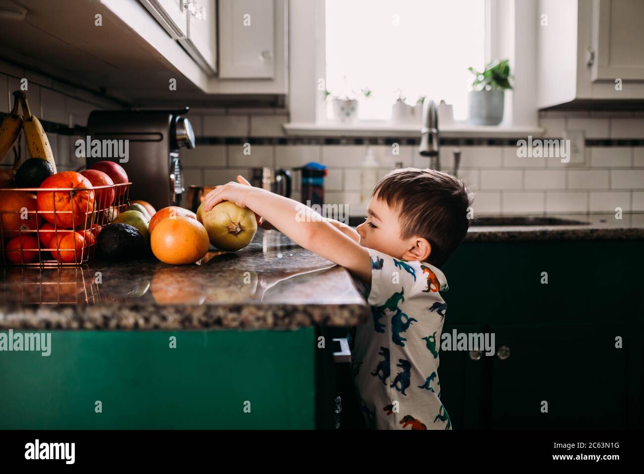 Young boy reaching for fruit on kitchen counter Stock Photo - Alamy