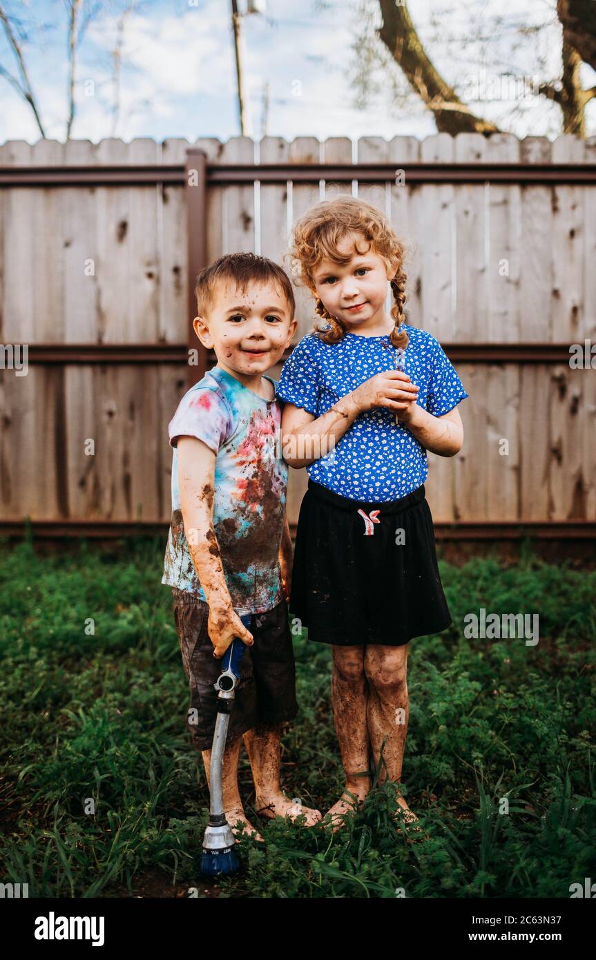 Two young kids playing in muddy backyard in spring Stock Photo - Alamy
