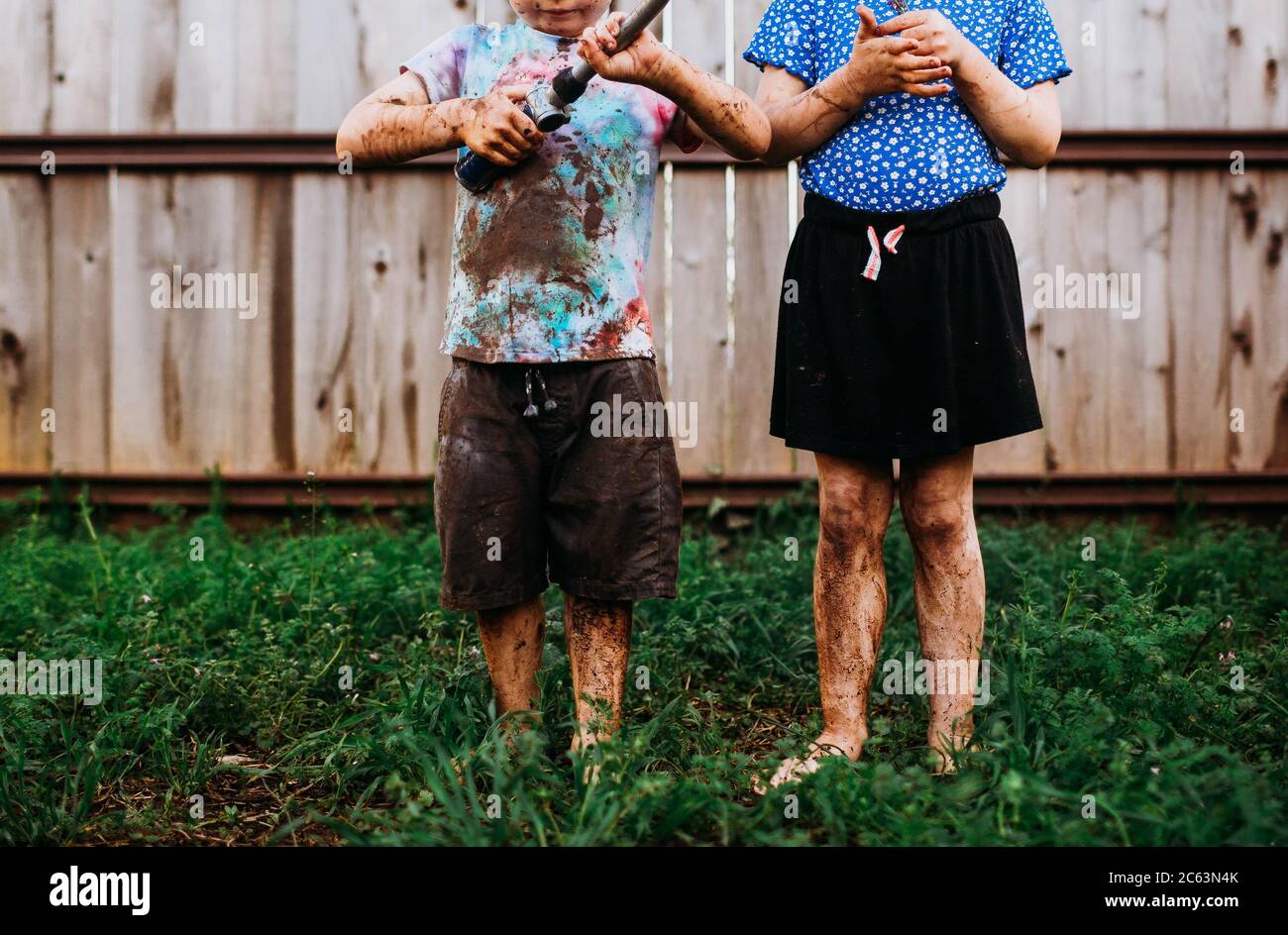 Young brother and sister standing outside covered in mud Stock Photo ...