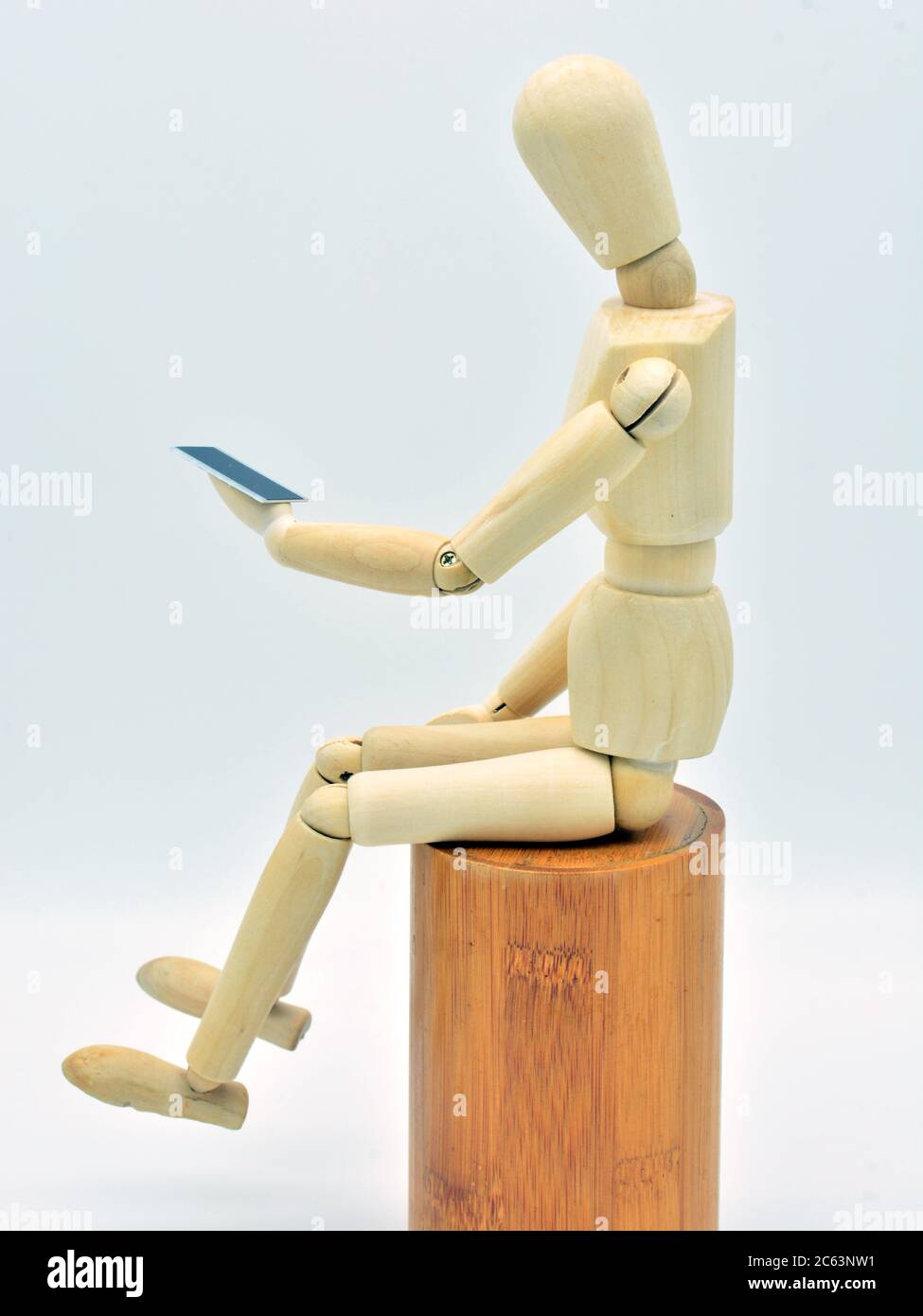 Wooden mannequin sitting, using a mobile phone Stock Photo - Alamy