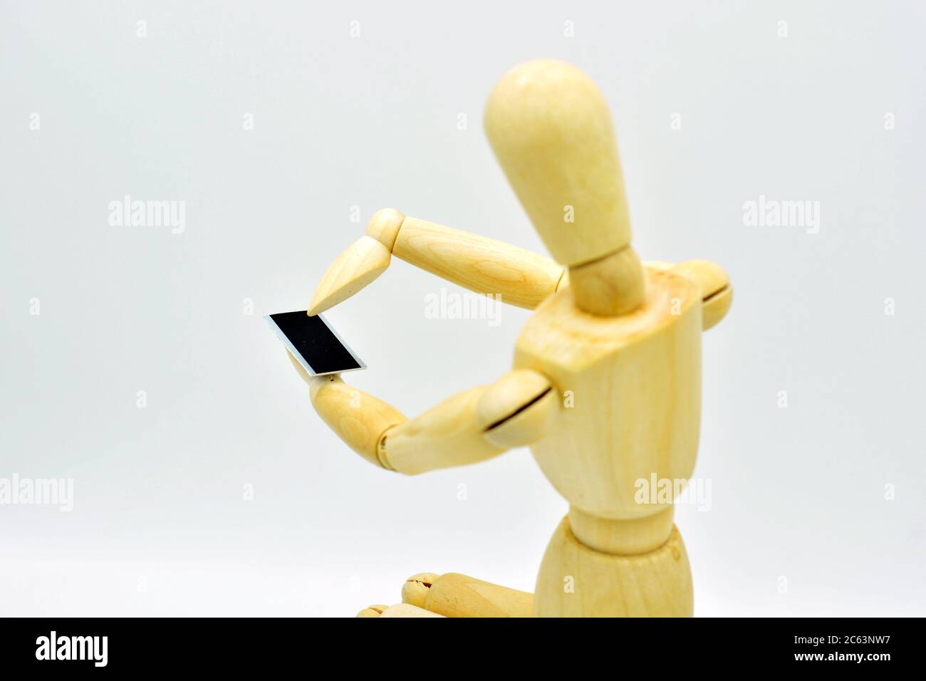 Wooden mannequin sitting, using a mobile phone Stock Photo - Alamy