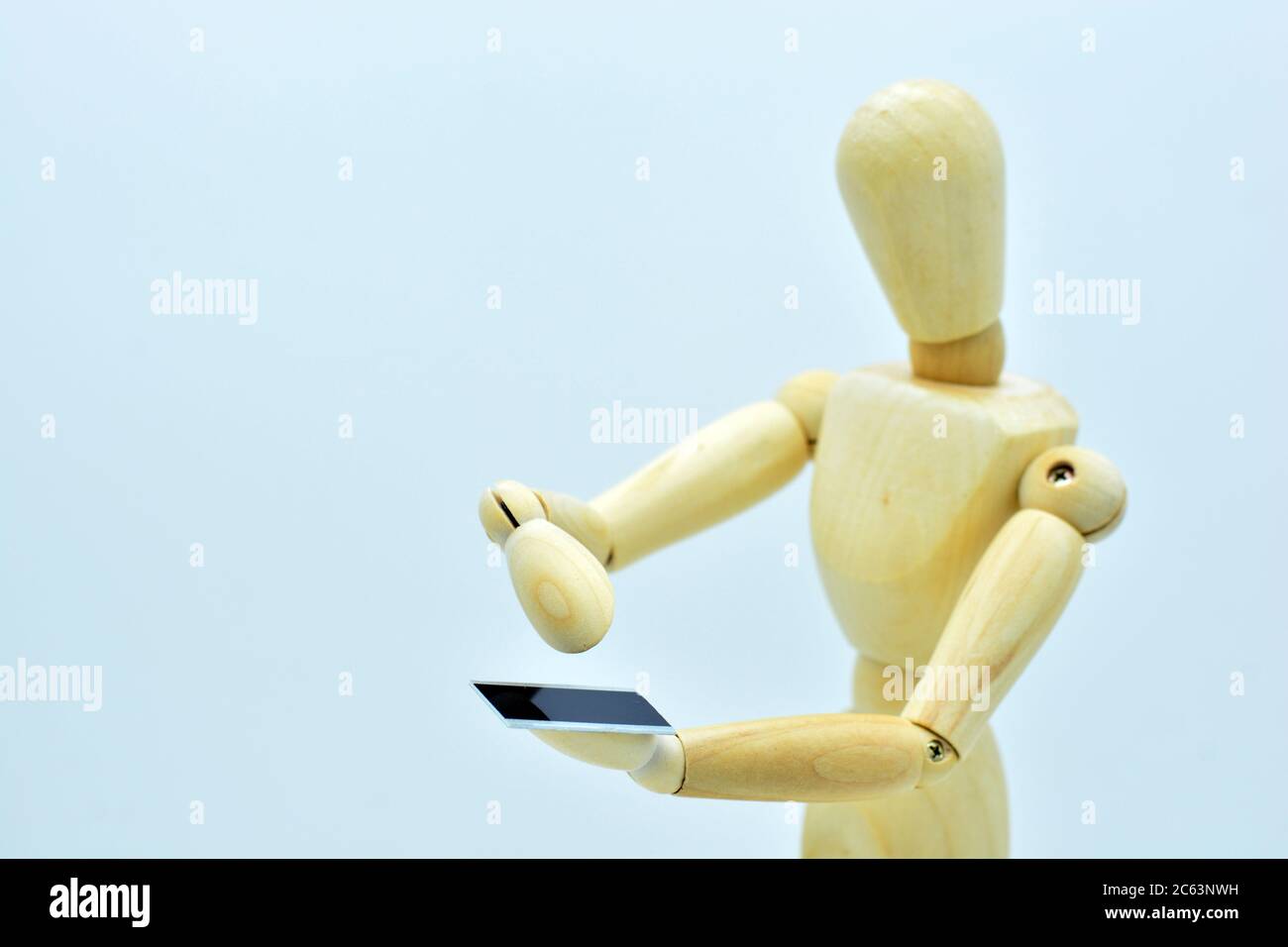 Wooden mannequin sitting, using a mobile phone Stock Photo - Alamy