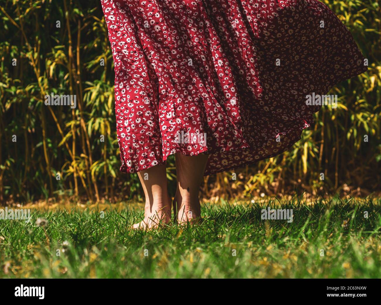 female feet from the ground from behind with dress moving in the wind ...