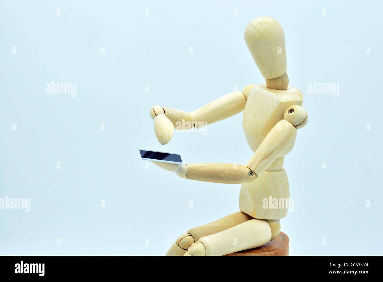 Wooden mannequin sitting, using a mobile phone Stock Photo - Alamy