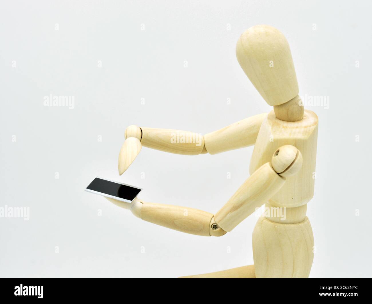 Wooden mannequin sitting, using a mobile phone Stock Photo - Alamy