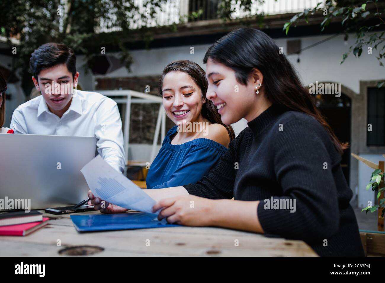 Young latin woman working with computer and her coworkers at the office ...