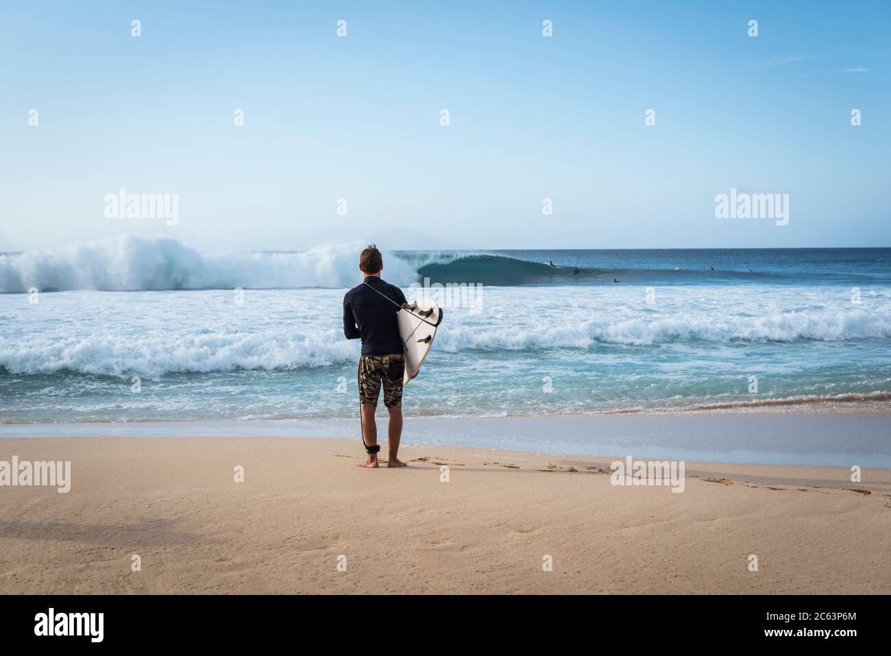 Young surfer is watching other people surfing big waves Stock Photo - Alamy