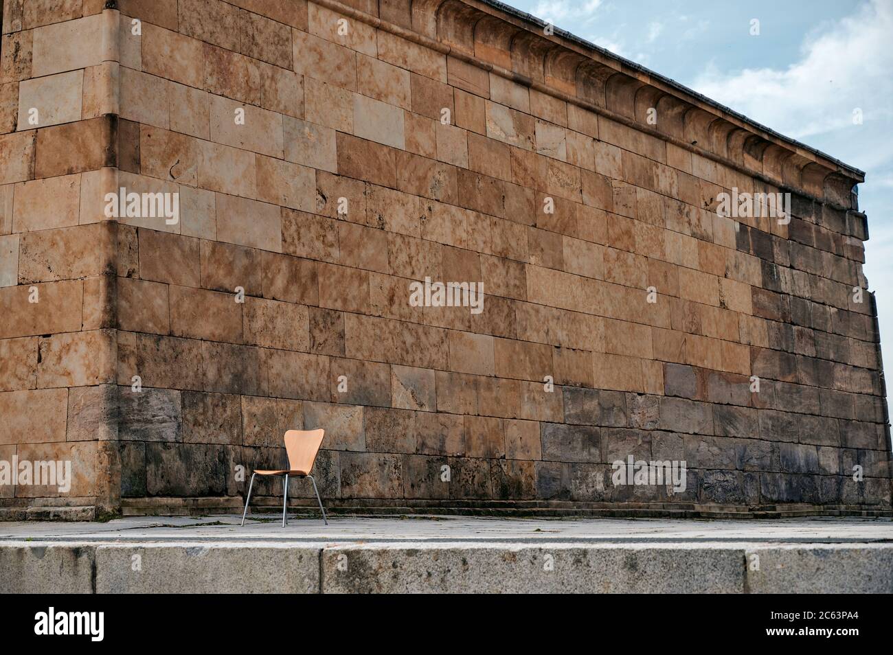 Modern chair placed near weathered block building with aged facade in ...