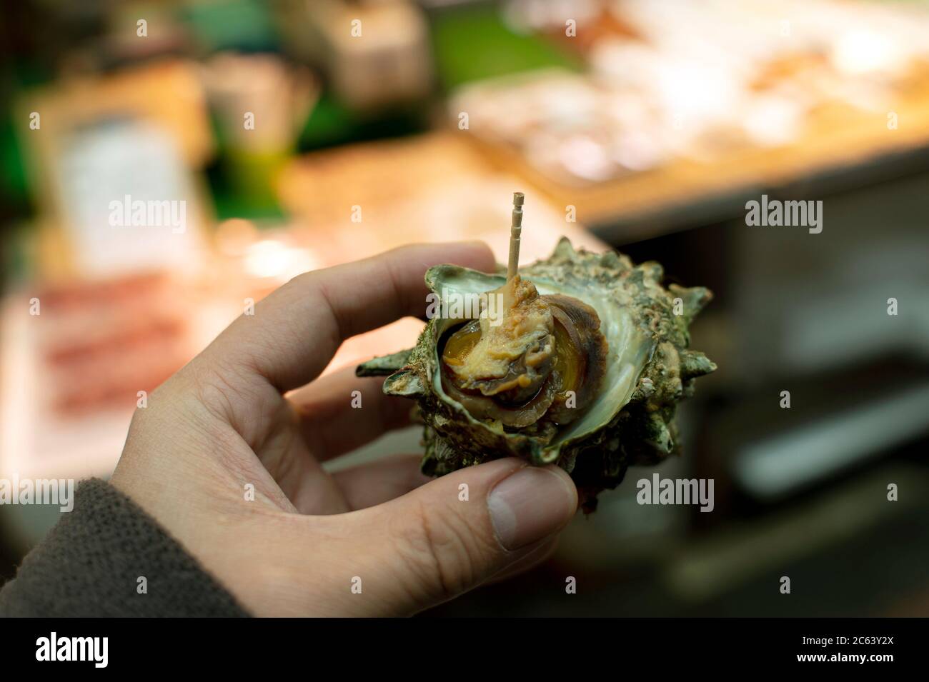 Human hands are carrying grilled sasae with a dipping stick. It is sold ...