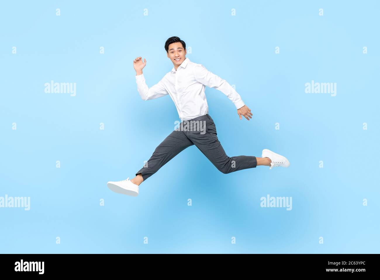 Happy smiling energetic Asian man in semi formal clothes jumping in mid ...