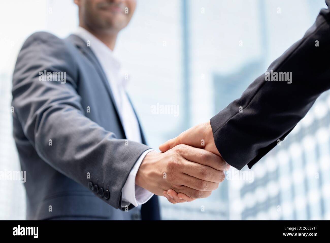 Businessman in formal suit making handshake with partner outdoors in ...