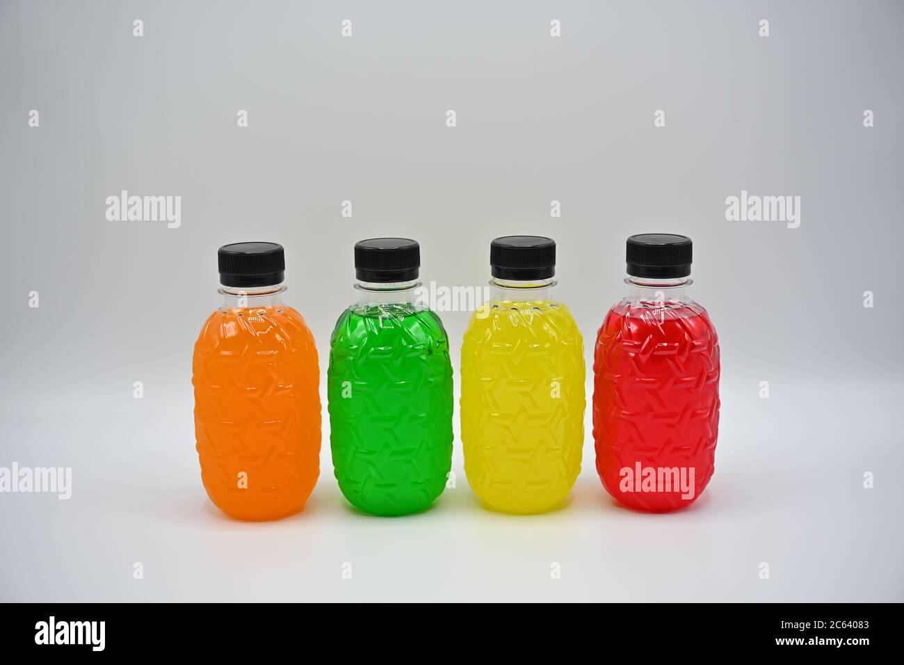 Plastic bottles of water of various colors arranged on a white ...