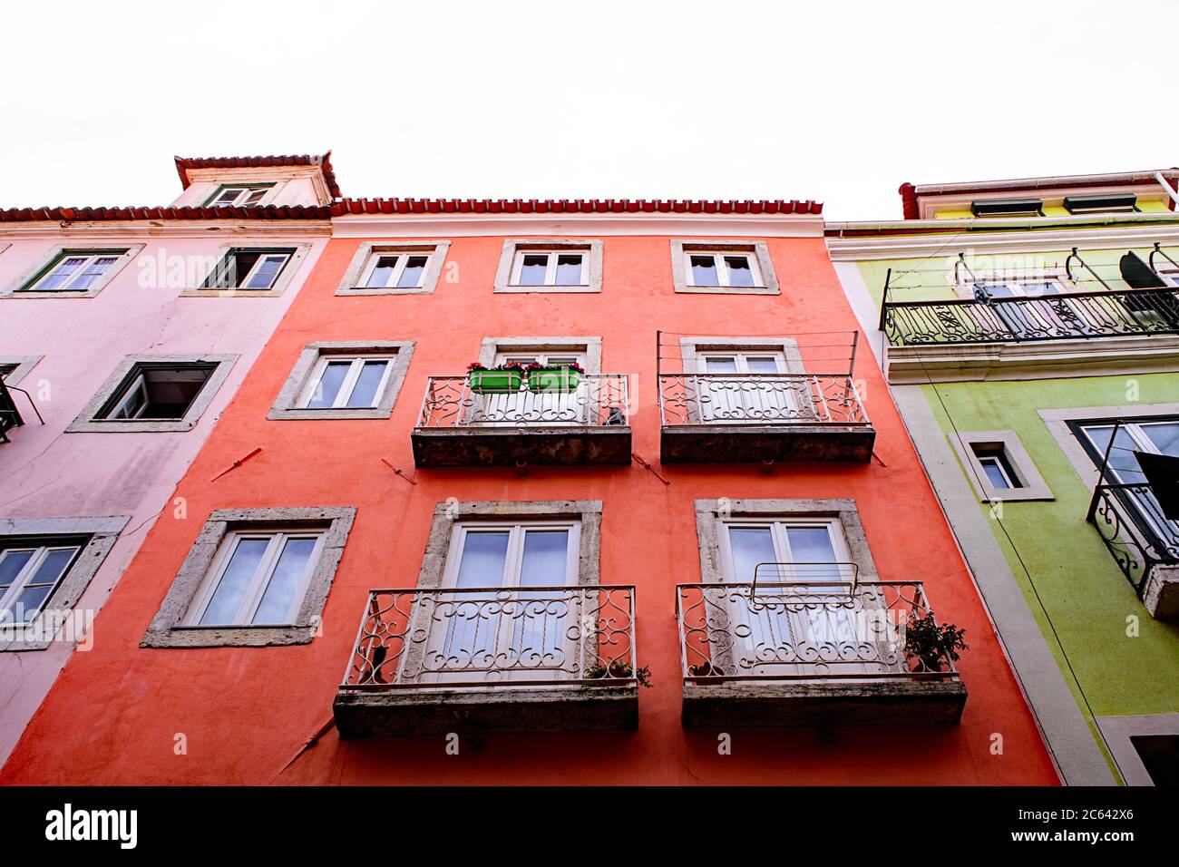 Pink, orange, and yellow-green apartment buildings with iron balconies ...